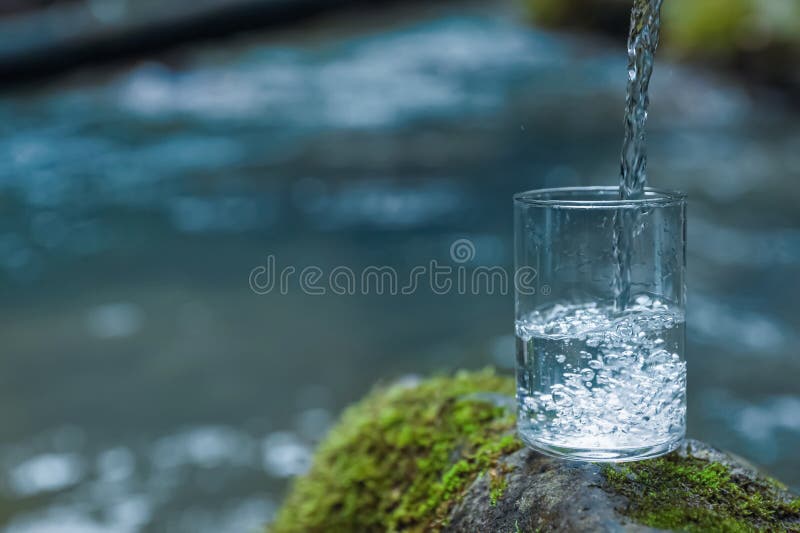 Fresh Water Pouring into Glass on Stone Near River. Space for Text ...