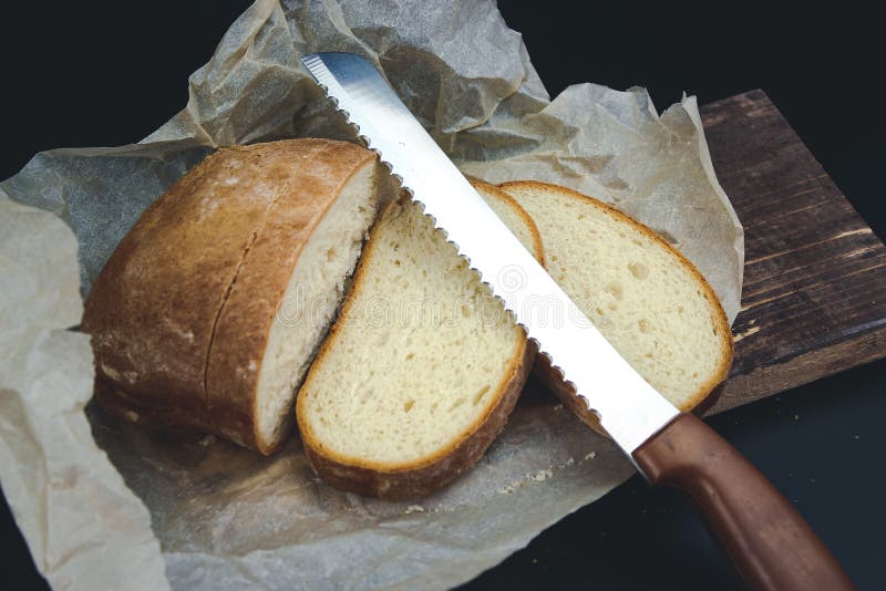 Freshly Baked Bread Cut into Chunks on a Wooden Board with Knife Stock ...