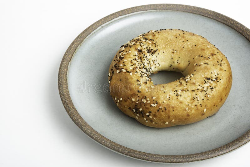 A Freshly Baked Single Bagel on a Ceramic Plate Stock Photo - Image of ...