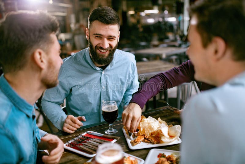 Freunde an Abendessen-trinkendem Bier Und Lebensmittel am Restaurant an ...