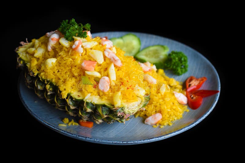 Fride Rice with Seafood in a Pineapple with Vegetables on Blue Plate ...