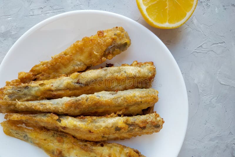 Fried Capelin Fish in a White Plate with Lemon Close Up on a Gray ...