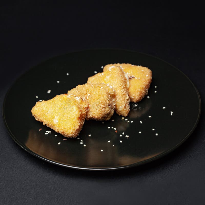 Fried Cheese Strips Breaded on a Black Plate on a Black Background ...