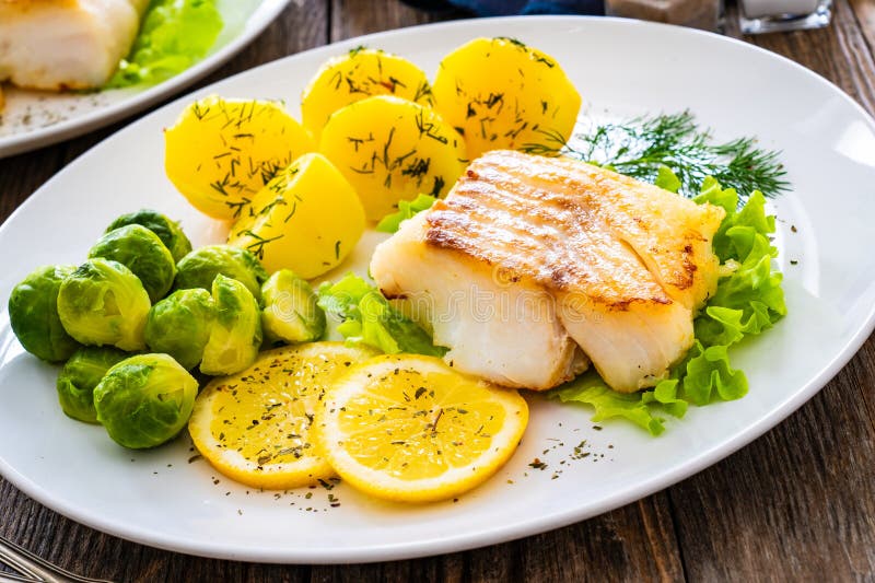 Fried Cod Loin, Boiled Potatoes and Cooked Brussels Sprouts on Wooden ...