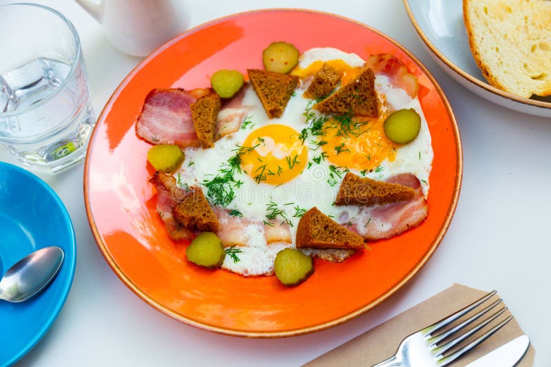 Fried Eggs with Bacon, Croutons and Pickles Cucumber. Traditional ...