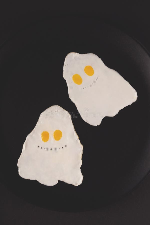 Fried Eggs in the Shape of Halloween Ghosts on Black Background Stock ...