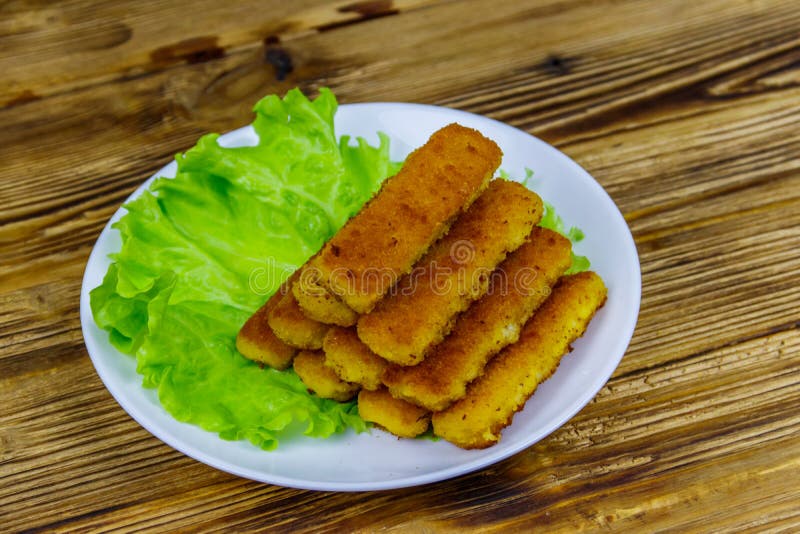 Fried Fish Fingers on a Plate with Lettuce on Wooden Table Stock Photo ...