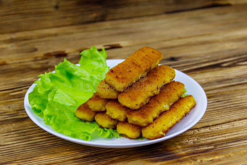 Fried Fish Fingers on a Plate with Lettuce on Wooden Table Stock Photo ...
