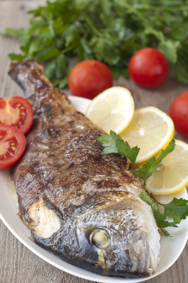 Fried Fish Garnished with Lemon, Tomato Stock Photo - Image of plate ...