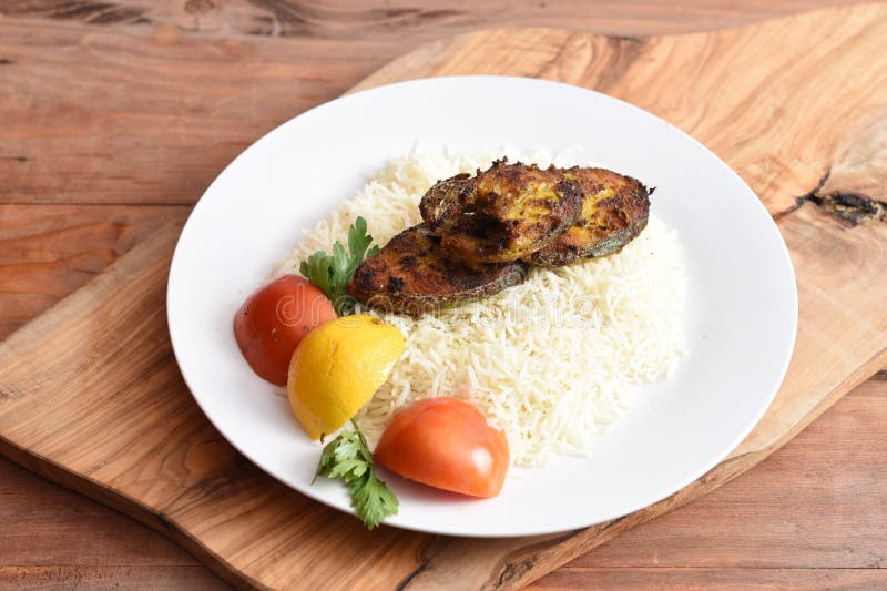 Fried Ilish Fish with Rice and Vegetables on a Wooden Surface Stock ...