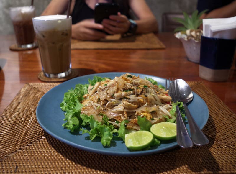 Fried Noodle Thai Style on a Blue Plate on a Brown Table with I Stock ...