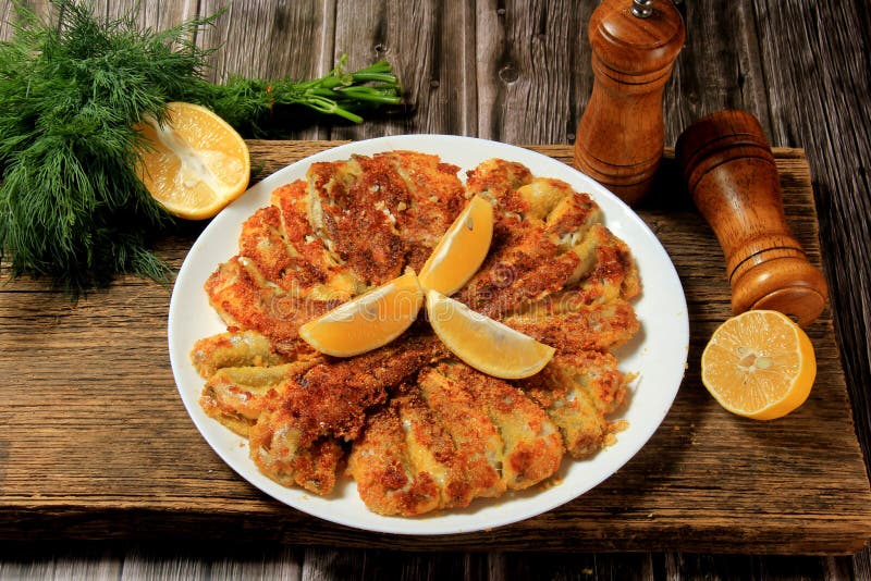 Fried Small Fish on a Plate, Decorated with Lemon Slices Stock Photo ...