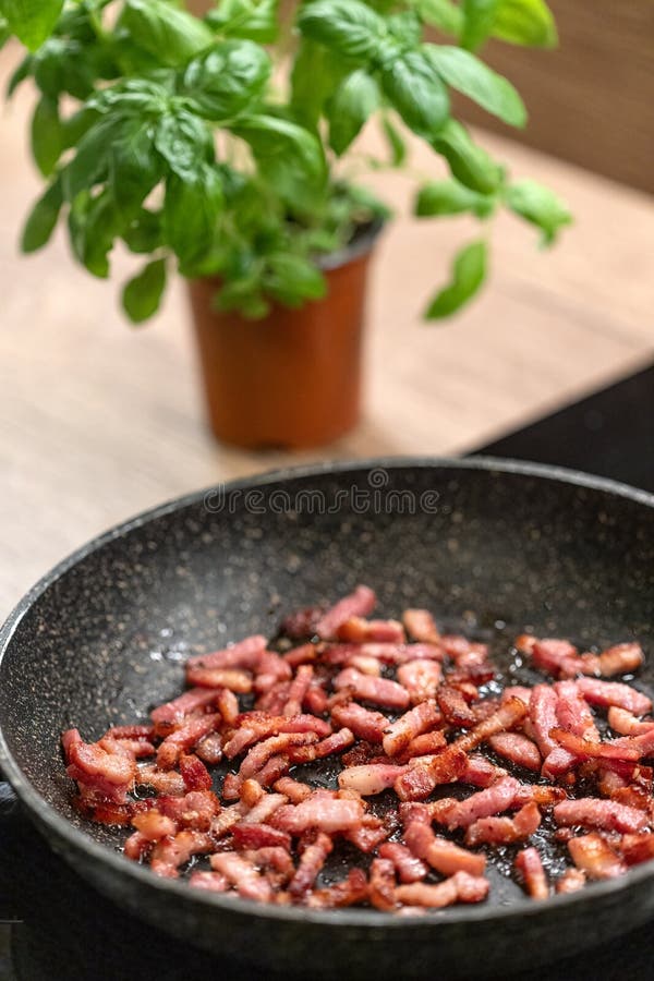Fried Small Pieces of Smoked Bacon in Frying Pan with Basil Plant in ...