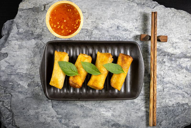 4 Fried Spring Rolls in a Black Ceramic Plate and Wooden Chopsticks ...