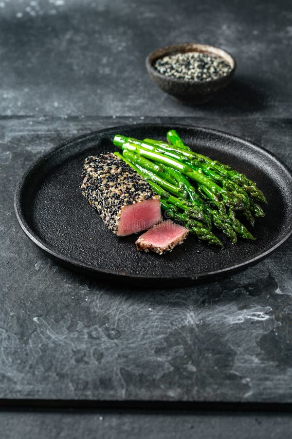 Fried Tuna Steak in Black Sesame with Asparagus on Black Plate Stock ...