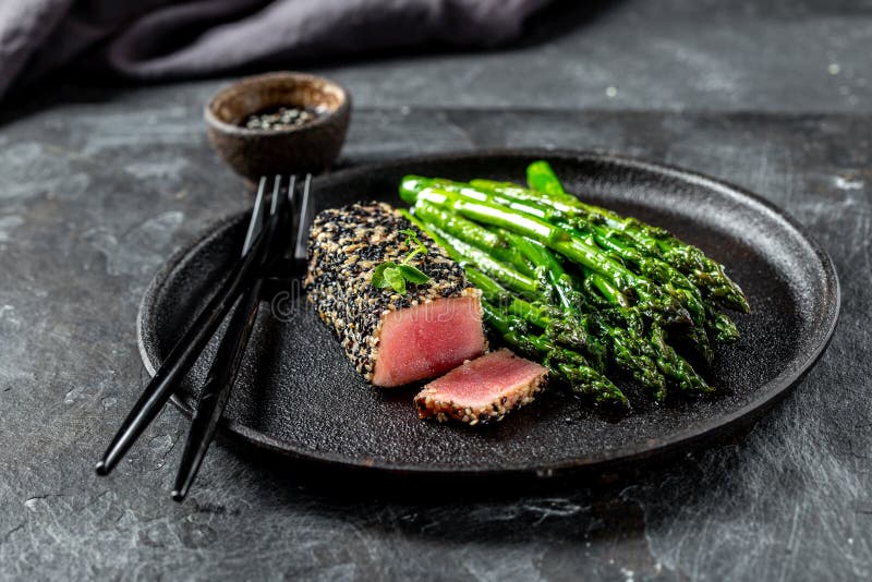 Fried Tuna Steak in Black Sesame with Asparagus on Black Plate Stock ...