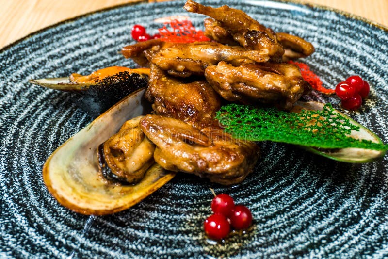 Fried Wings with Mussels in a Black Plate Stock Photo - Image of ...
