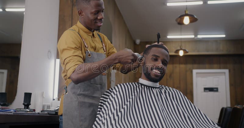 Friendly Barber in Apron Working with Client Using Shaving Machine and ...