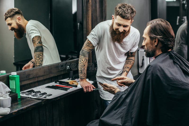 Friendly Barber Smiling while Client Showing Screen of Smartphone Stock ...