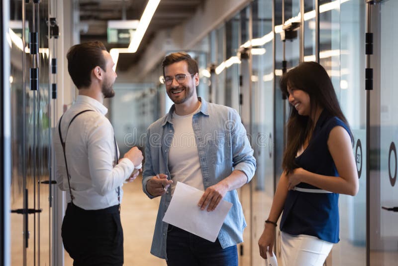 Friendly Diverse Office Workers Standing in Hallway Chatting during ...