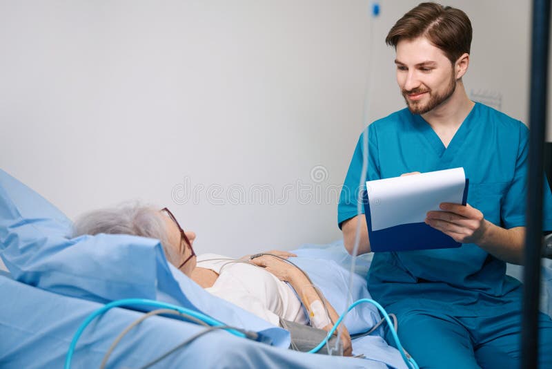 Friendly Nurse Sits Near a Patient Lying on the Bed Stock Image - Image ...