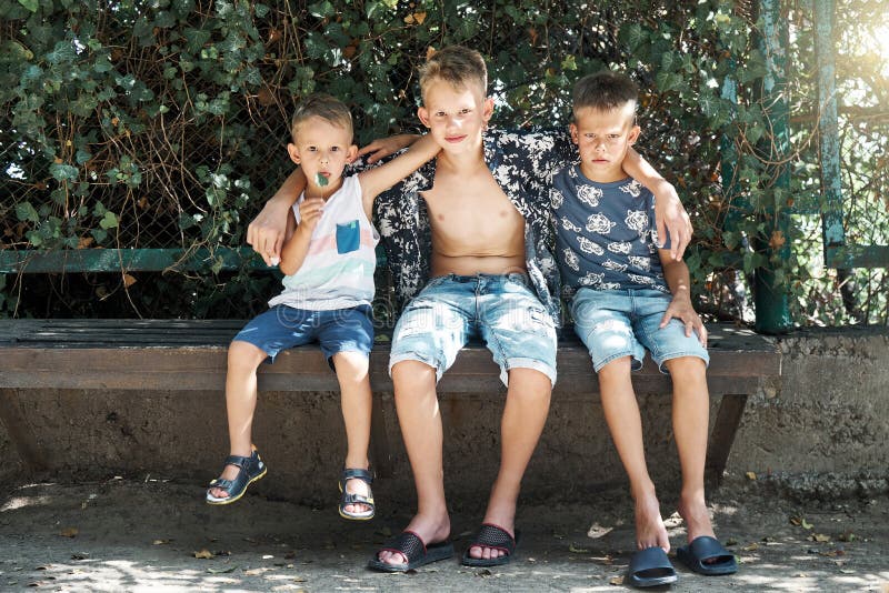 Friendly Siblings Sit on Stone Bench Resting in Tree Shadow Stock Photo ...