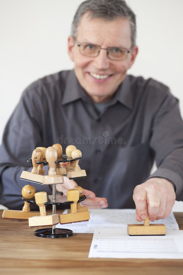Friendly Smiling Clerk Stamping a Document at a Desk in an Office Stock ...