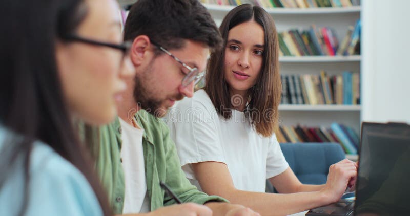 Friendly Students Sit at Desk in Library Writing, Discuss Collaborative ...