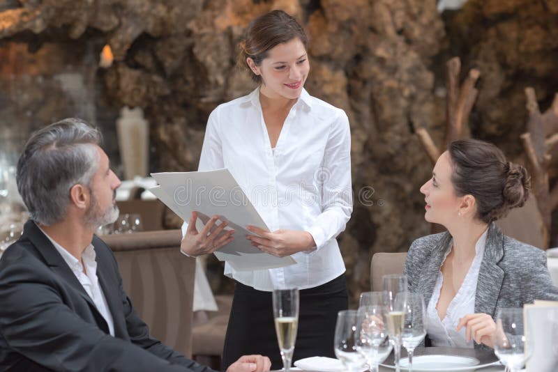 Friendly Waitress Serving Meal for Guests at Table in Restaurant Stock ...
