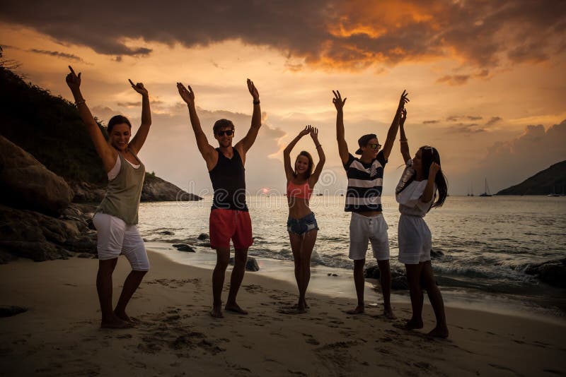 Friends on beach at sunset stock image. Image of holiday - 100070827