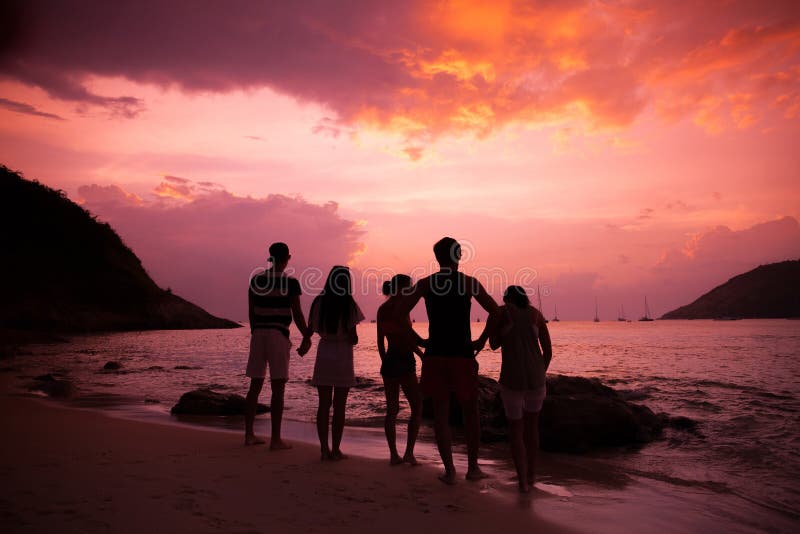Friends on beach at sunset stock image. Image of group - 147381973