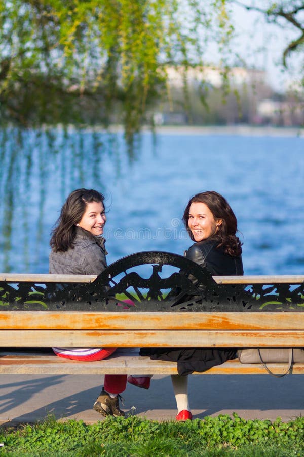 Friends on a bench in park stock photo. Image of camera - 193819606