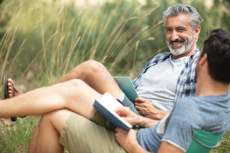 Friends in Campsite Reading Book Stock Photo - Image of cool, nature ...