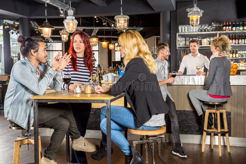 Friends Conversing while Sitting at Table in Bar Stock Photo - Image of ...