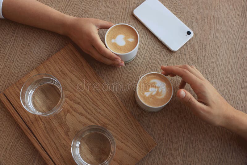 Friends Drinking Coffee at Wooden Table in Cafe, Top View Stock Photo ...