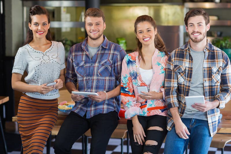 Friends Posing with Mobile Phones and Digital Tablets in Restaurant ...