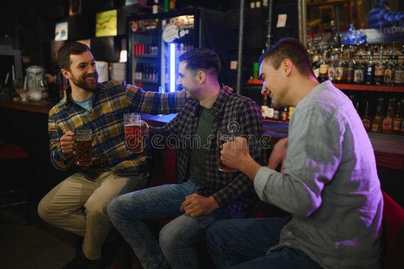 Friends Resting in the Pub with Beer in Hands. Having Conversation ...