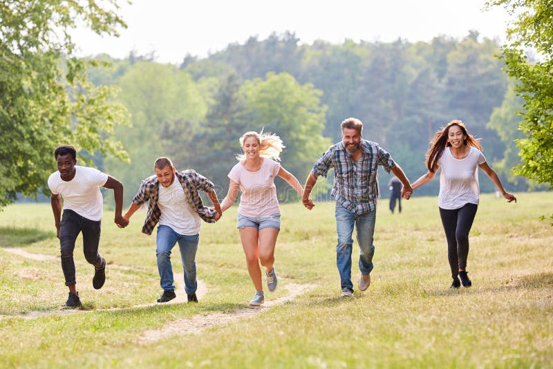 Friends Run Together Over a Meadow Stock Image - Image of interracial ...