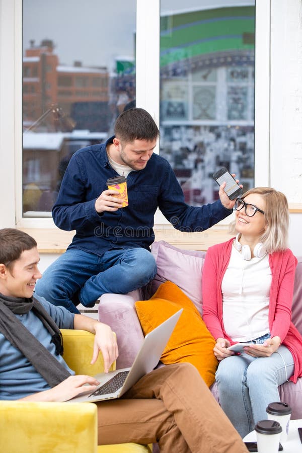 Friends Sit on the Couch, Chatting and Using a Smartphone, Desktop ...