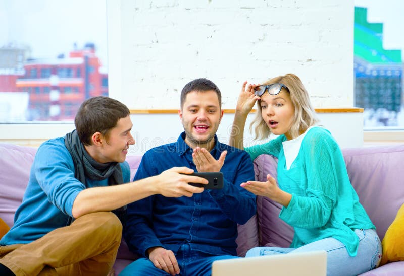 Friends Sit on the Couch, Chatting and Using a Smartphone, Desktop ...