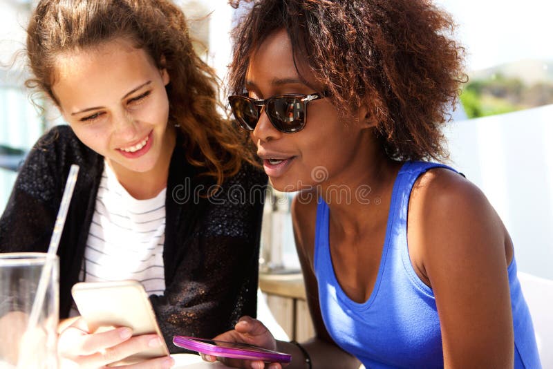 Friends Sitting at Cafe Looking at Cell Phone Stock Image - Image of ...