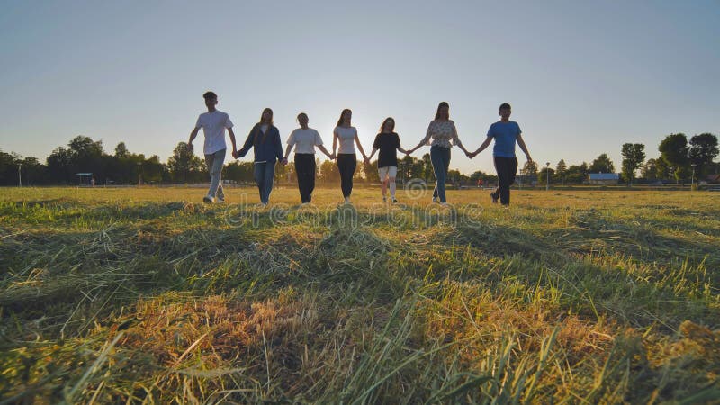 Friends at Sunset Holding Hands Walking Towards the Sun. Stock Photo ...