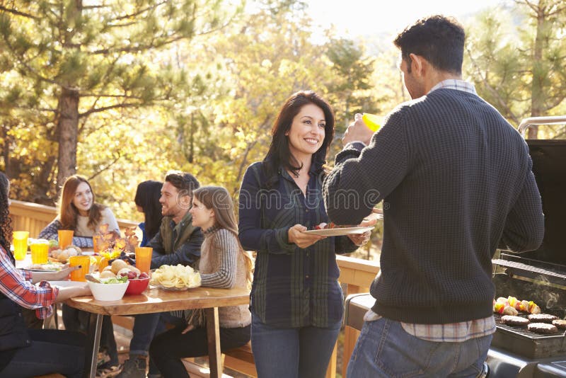 Friends at a Table and Two Talking by Grill at a Barbecue Stock Photo ...