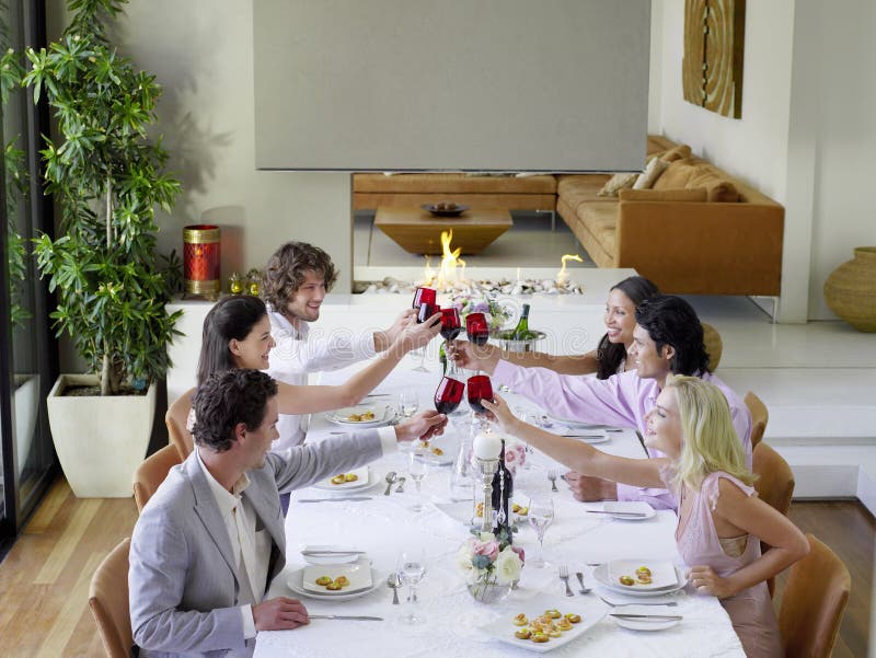 Friends Toasting Wineglasses Across Dinner Table Stock Photo - Image of ...