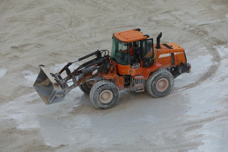 Front Loader with Small Wheels Against the Background of a Large Pile ...