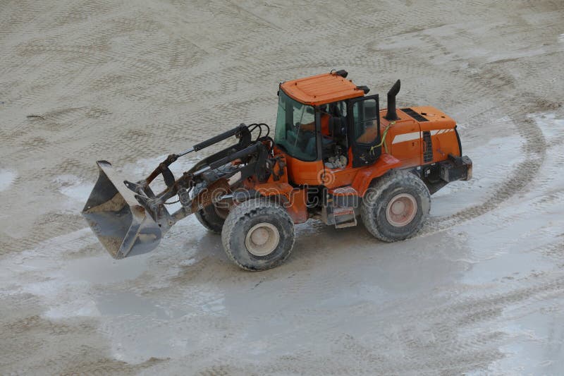 Front Loader with Small Wheels Against the Background of a Large Pile ...
