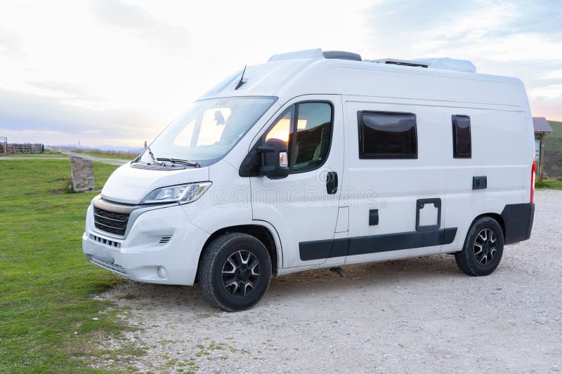 Front and Side of a Modern White Camper Van with Roof Cooler, Camped in ...