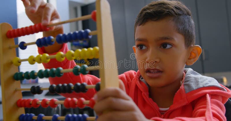 Front View of Asian Schoolboy Solving Math Problem with Abacus at Desk ...