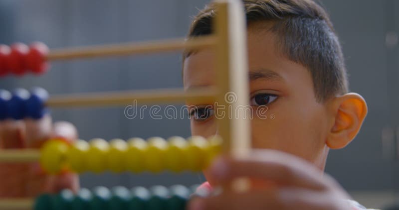 Front View of Asian Schoolboy Solving Math Problem with Abacus at Desk ...