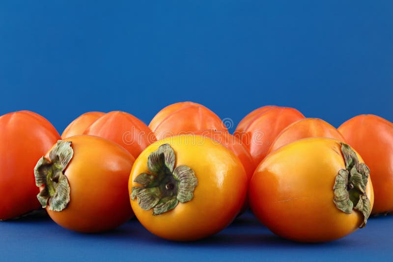 Front View of a Bunch of Persimmon Fruit on a Blue Background Stock ...